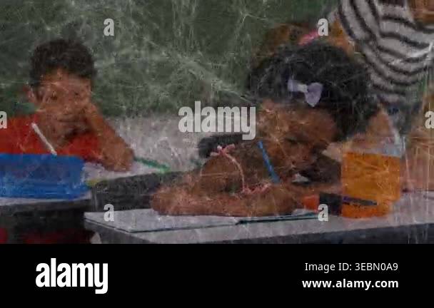 Girl writing with pencil pausing upon teacher leaning to check work ...