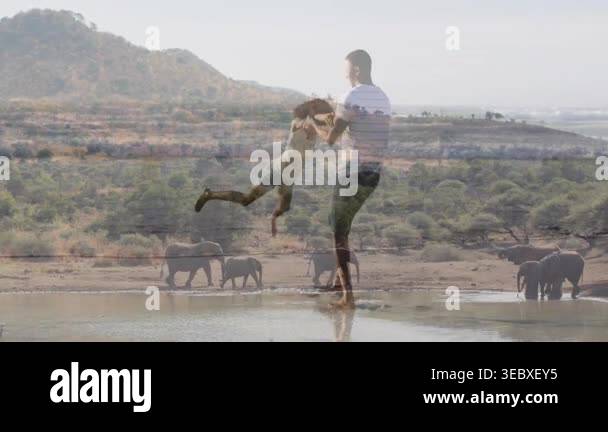 Dad lifting child, swinging outward and back on wildlife bank with ...