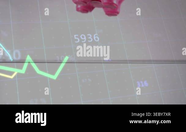 Piggy bank dropping into water making splashes while finance charts ...