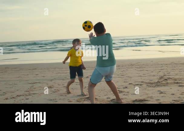Young boys passing and kicking a soccer ball barefoot on the sand ...