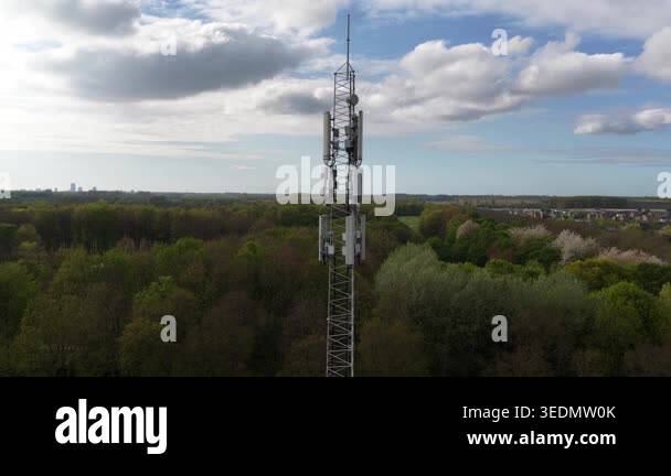 Aerial footage descending alongside a tall telecommunication tower ...