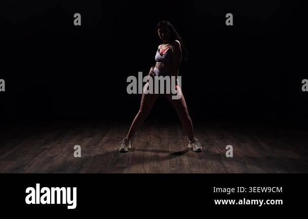 Woman dancing twerk in low light, emphasizing her silhouette and ...