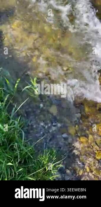 Vertical shot of fast river water flowing over rocks in sunny day Stock ...
