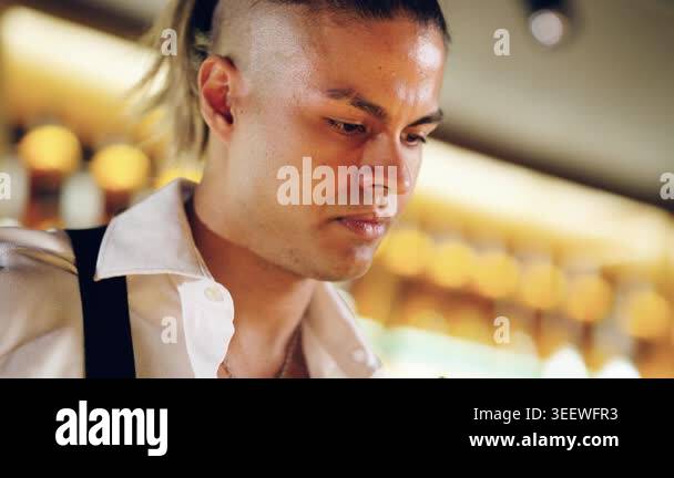 Professional young bartender with a modern hairstyle carefully pouring ...