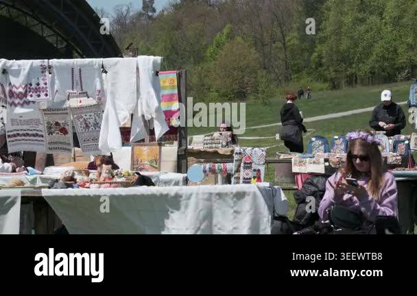 People browse colorful stalls filled with handmade goods on a sunny day ...