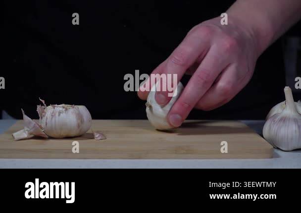 Preparing whole garlic for roasting by cutting the top close-up Stock ...