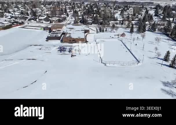 Aerial view of a snowy suburban neighborhood. Frozen pond dominates the ...