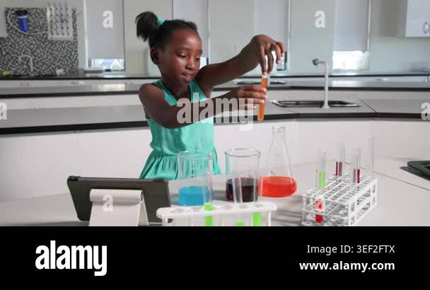Female child in teal top following tablet guide, pouring orange tube ...