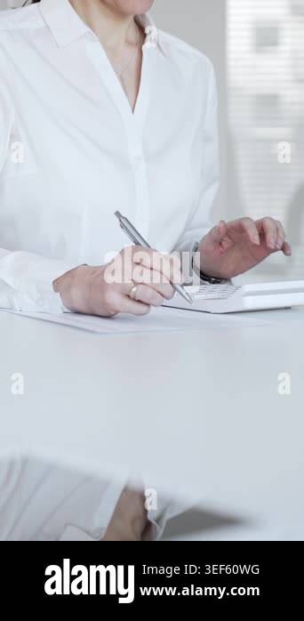 Businesswomans hands calculating with pen and calculator amid documents ...