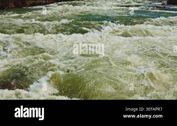 Strong waves and currents move rapidly in a river. The water appears ...
