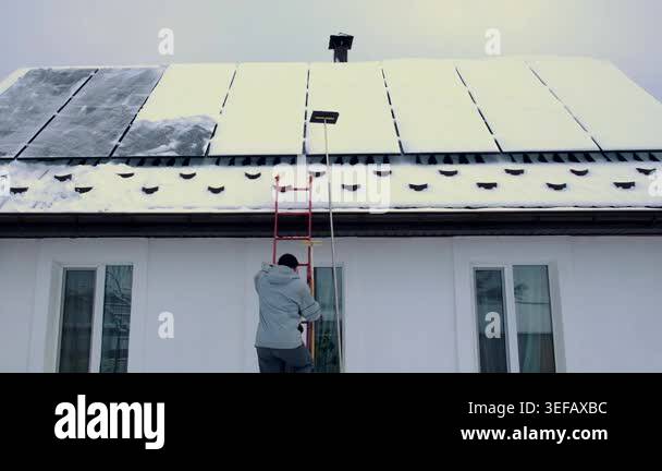 A man clears snow from solar panels. Selective focus. Nature Stock ...