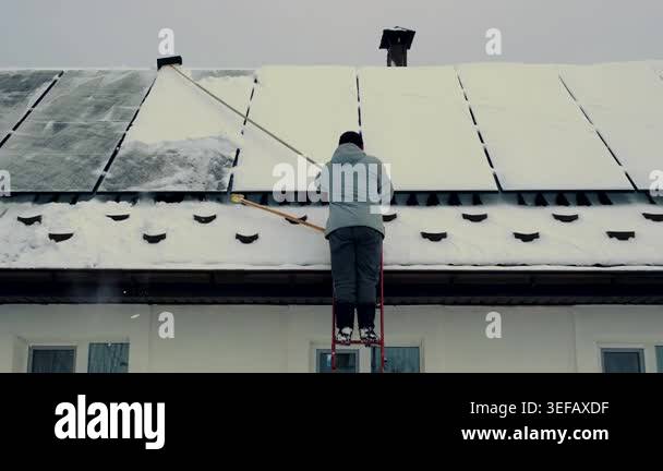 A man clears snow from solar panels. Selective focus. Nature Stock ...
