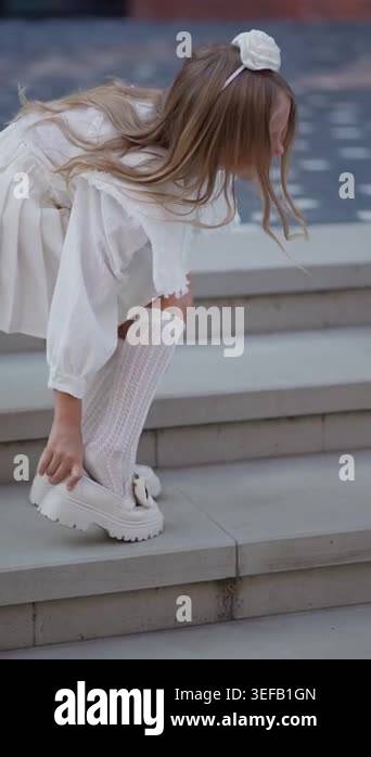 Little girl in white dress with long hair, flower headband leaning on ...