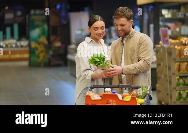 Joyful young couple shopping for fresh produce in the grocery store ...