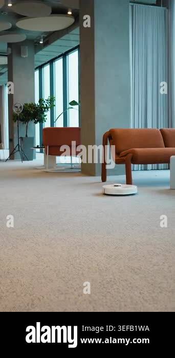 Modern robotic vacuum cleaner automatically cleaning the carpeted floor ...