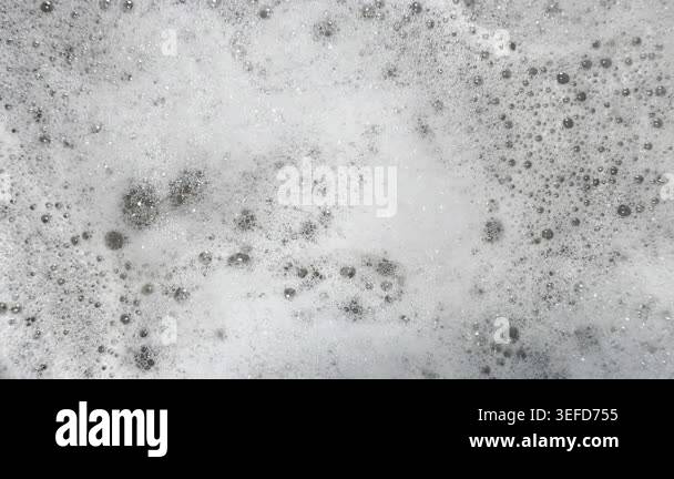 Soap suds jiggle in kitchen sink, creating an abstract background plate ...