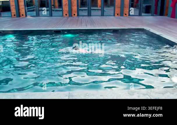 Female athlete swims front crawl in backyard pool with glowing ...