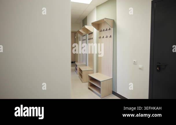 Corridor features wall-mounted coat racks and integrated shoe benches ...