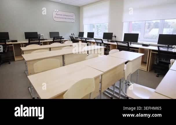 Empty well-lit classroom waits for students with tidy desks and chairs ...