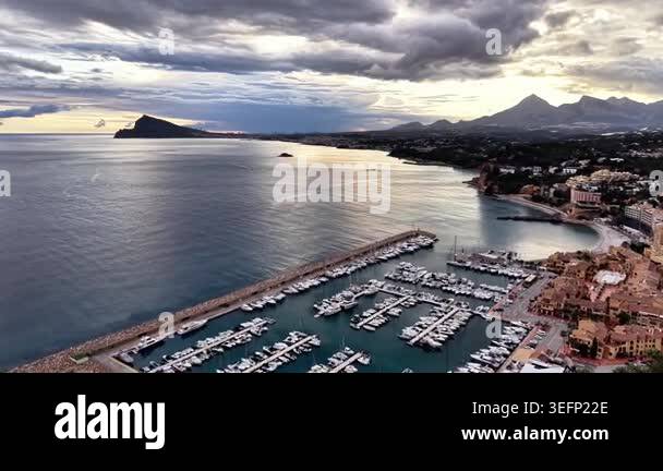 Twilight harbor with dramatic clouds and moody reflections over marina ...