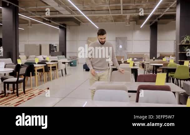 Man shopping for furniture, examining chairs and tables in a modern ...