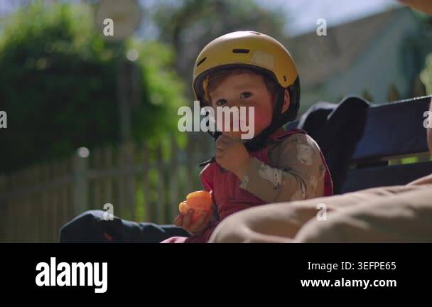 Young child eating citrus fruit outside, briefly removing piece from ...