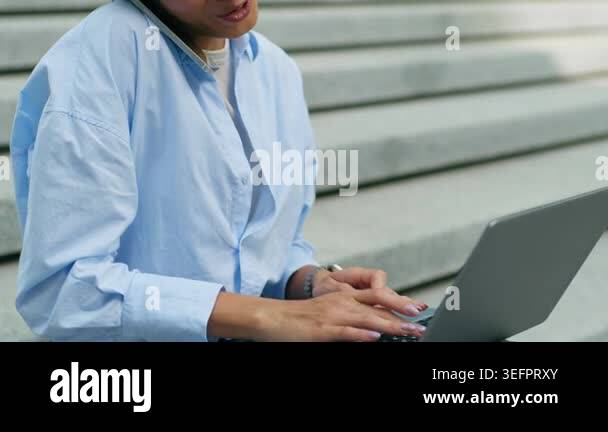 Smiling African American business woman talking on phone working laptop ...