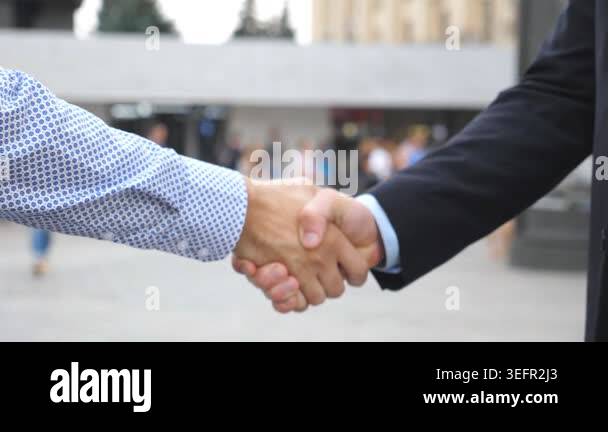 Two young confident businessmen shaking hands with blurred city ...