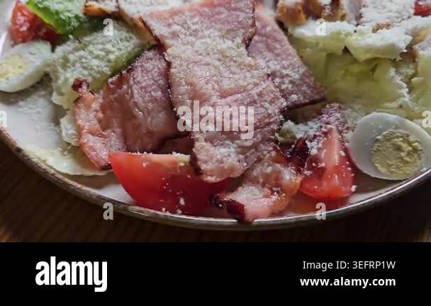 Traditional caesar salad in a white bowl with leaves and a sauce boat ...