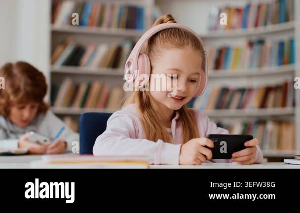 A girl with long blonde hair wearing headphones is focused on her ...