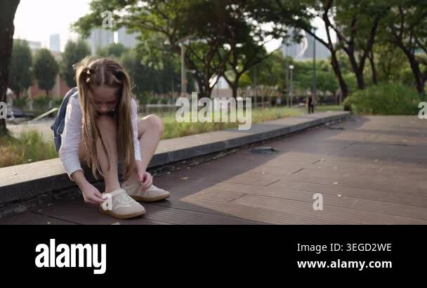 Portrait of junior schoolgirl with pigtails fastens velcro on shoe in ...