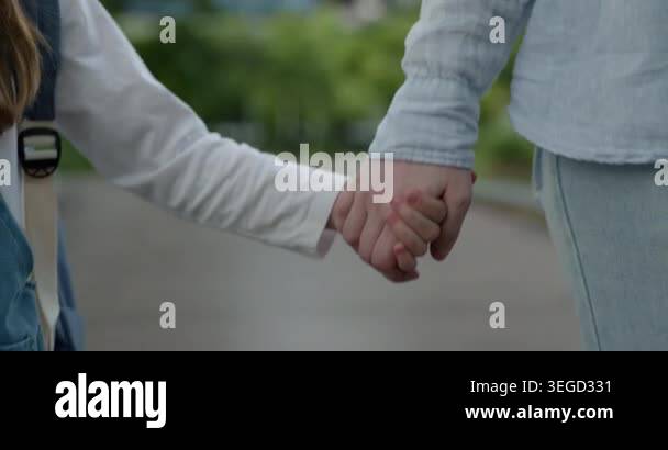 Crop view of mother and little daughter join hands as walk together in ...