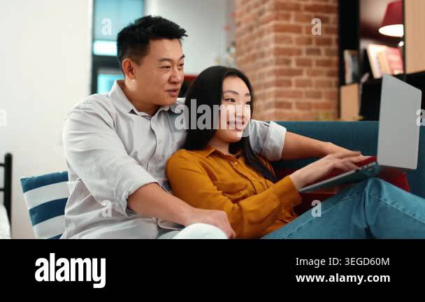 A man with light skin sits behind a woman with light skin on a couch ...