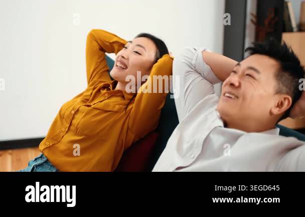 A man with dark hair and a woman with long black hair sit comfortably ...