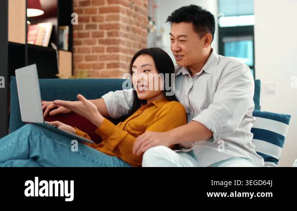 A man with dark skin and a woman of Asian descent sit side by side on a ...