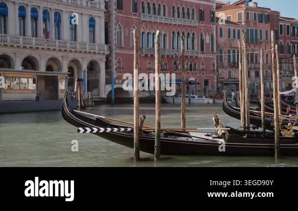 Traditional Venetian gondolas with gondoliers near pier in Venice ...