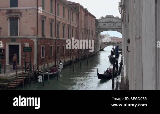 Peaceful Venice canal with gondolas, historic buildings, a cloudy sky ...