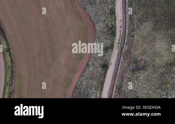 Aerial top down view of a narrow irrigation canal winding through rural ...
