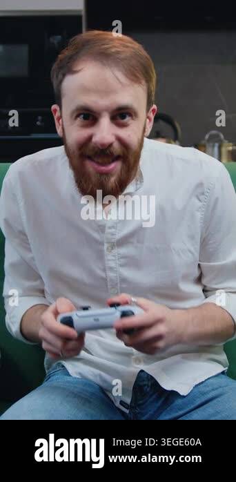 Attractive young man playing video game on gamepad sitting in living ...