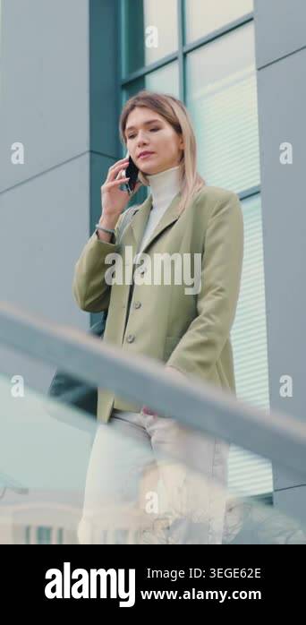 Pretty young smiling woman looking on watch while talking on smartphone ...