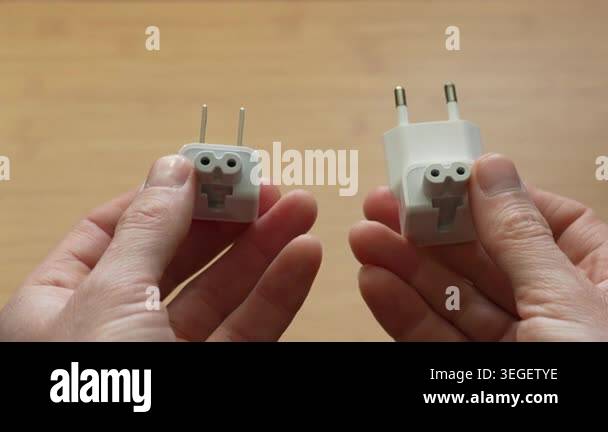Close up front view of male hands holding US and European power plugs ...