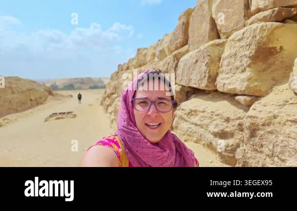 Smiling woman wearing a headscarf or hijab taking a selfie video while ...