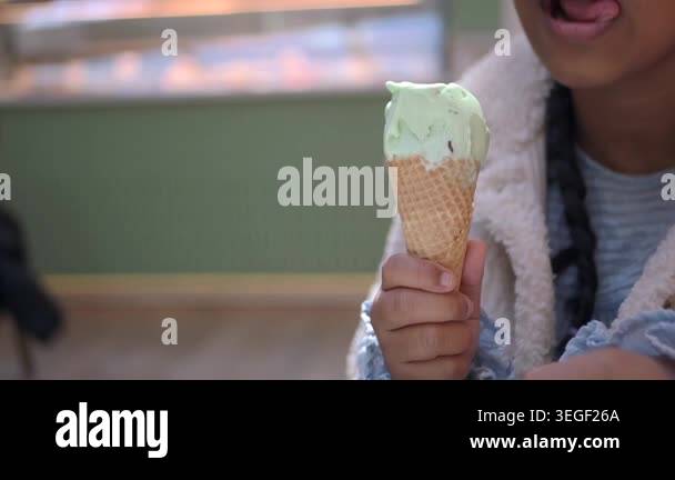 A person holds a cone of mint ice cream while sitting indoors Stock ...