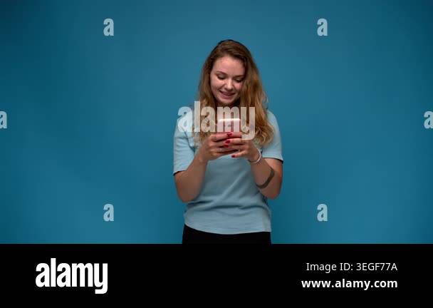 Happy young woman smiling while texting and browsing on her mobile ...