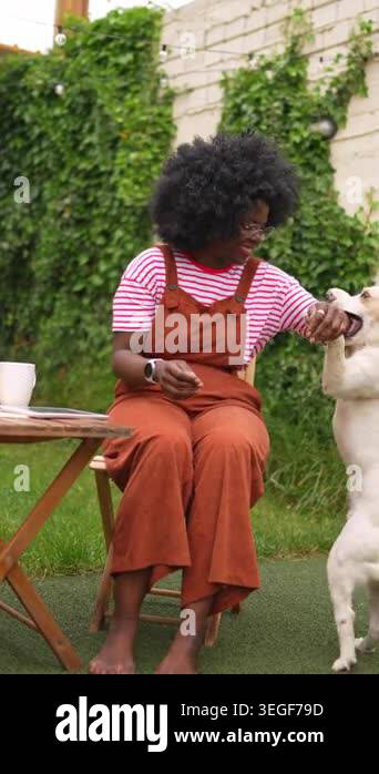 Smiling woman with afro hairstyle sitting on a chair and playing with ...