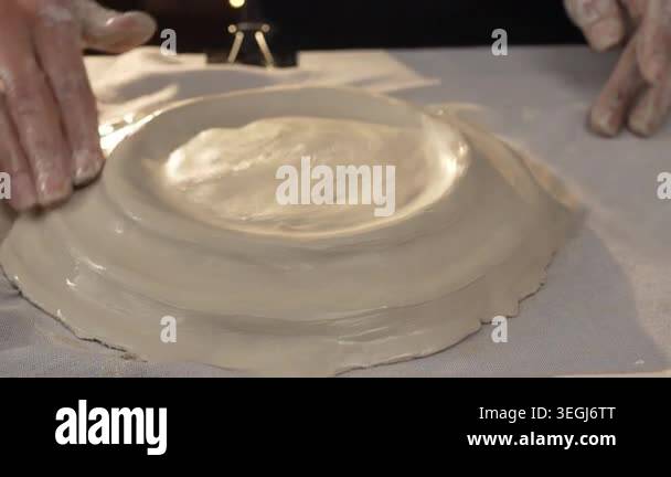 Close-up of Female hands forming plate from wet clay sitting on table ...