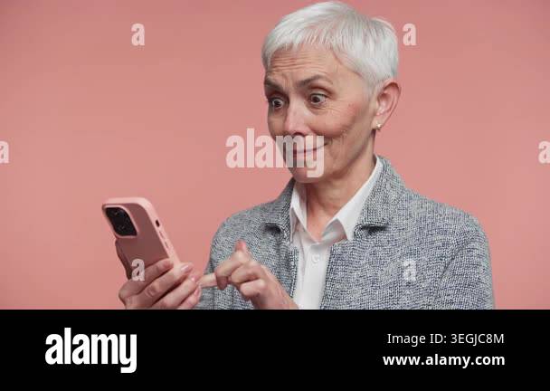 Older woman with short gray hair smiles brightly while reading good ...