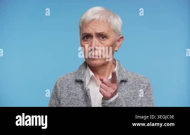 Mature woman with short gray hair points forward with a serious warning ...