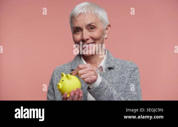 Older woman with short gray hair smiles while putting a coin into a ...