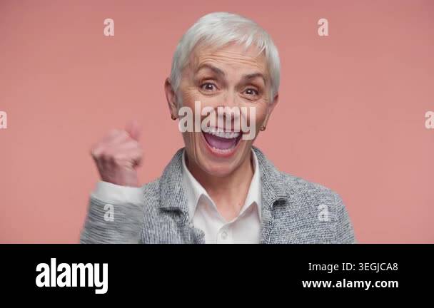 Energetic older woman with short gray hair smiles widely and raises her ...
